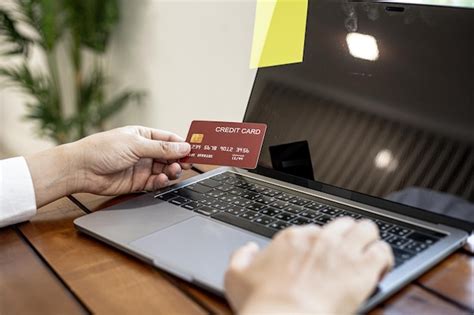 Premium Photo A Man Holds A Credit Card And Uses A Laptop He Is