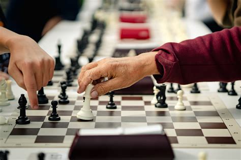 체스 어린이와 노인 손 폰 조각을 움직이는 꼬마 소년 체스 판을 생각하는 남자 아이가 노인에게 체스를 가르친다 나이 든 선수들과 젊은 선수들이 밖에서 놀고 있습니다 2명에