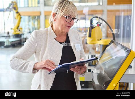 Female Engineer Programming An Industrial Robot With Gripper Arm In A Modern Factory Setting