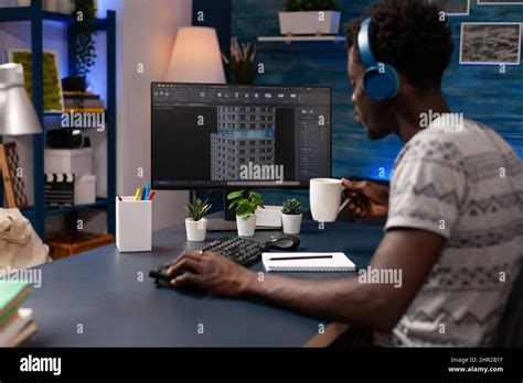 Young Architect Wearing Headphones Looking At Building Structure Analyzing Prototype On Computer