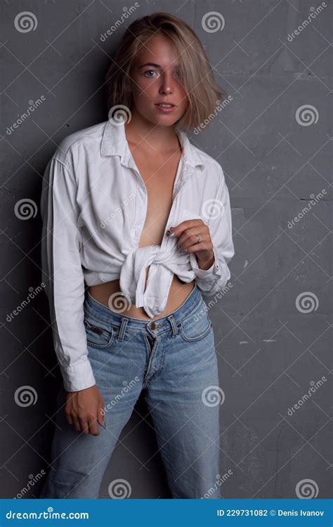 Young Woman With A Beautiful Figure In Jeans And An Unbuttoned Shirt