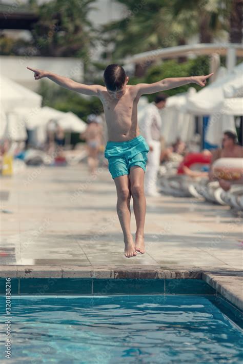 Caucasian Boy Having Fun Making High Jump To Plunge Into Swimming Pool