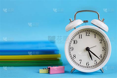 蓝色背景上的课本和闹钟。回到学校。教育或商业