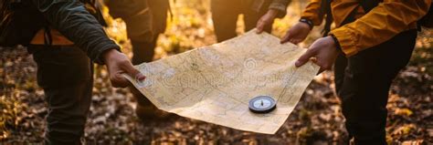 Scouts Navigate Together Using A Map And Compass In The Forest During A