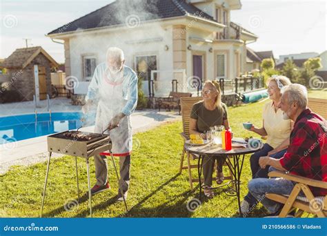 Elderly Neighbors Having Backyard Barbecue Party By The Swimming Pool