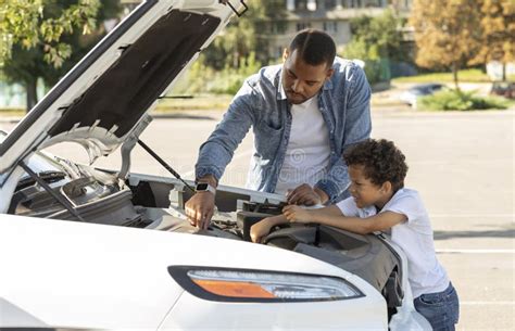Black Father And Preteen Son Checking Car Engine Outdoors Stock Image