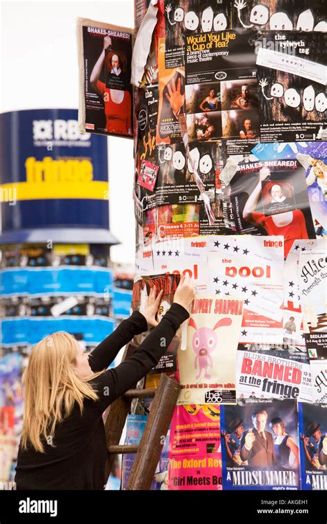 Woman Putting Up Advertising Poster At Edinburgh Festival Fringe Stock