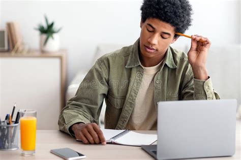 Thoughtful Black Teen Guy Passing Hard Exam Or Online Test On Laptop At