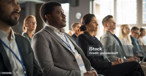 African Man Sitting In A Crowded Auditorium At A Tech Conference