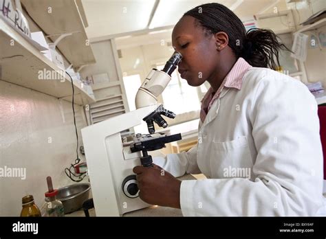 A Female Lab Technician Looks Through A Microscope At A Hospital In