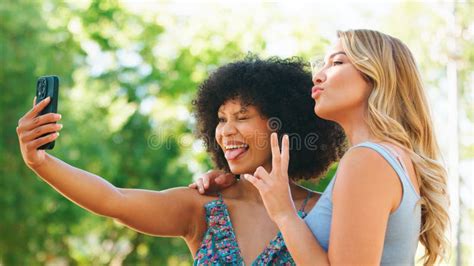 Same Sex Female Couple Or Friends Taking Selfie In Sunny Park During