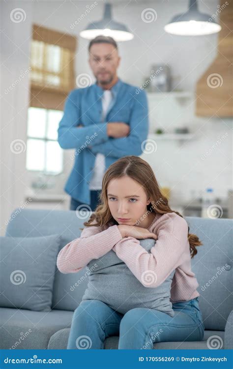 Dad Standing Behind The Sofa On Which Daughter Is Sitting Stock Image