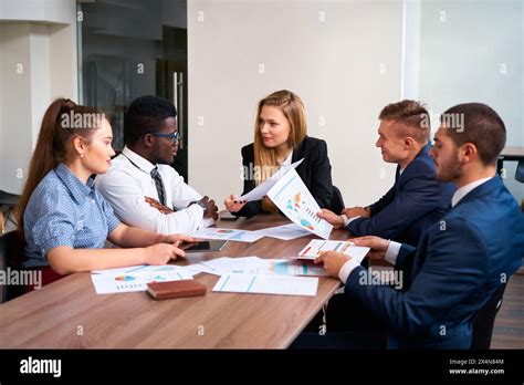 Multiracial Team Analyzes Graphs In Office African Man In Suit Shares