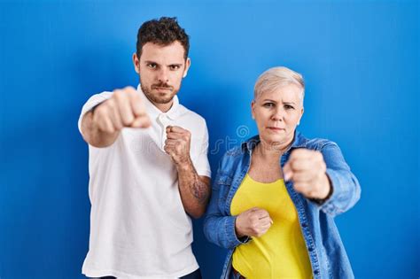 Young Brazilian Mother And Son Standing Over Blue Background Punching
