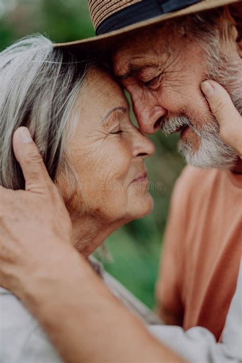 Portrait Of Senior Couple In Love Standing Outdoor In Nature Stroking