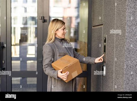 Woman Using Intercom At Building Entrance Stock Photo Alamy