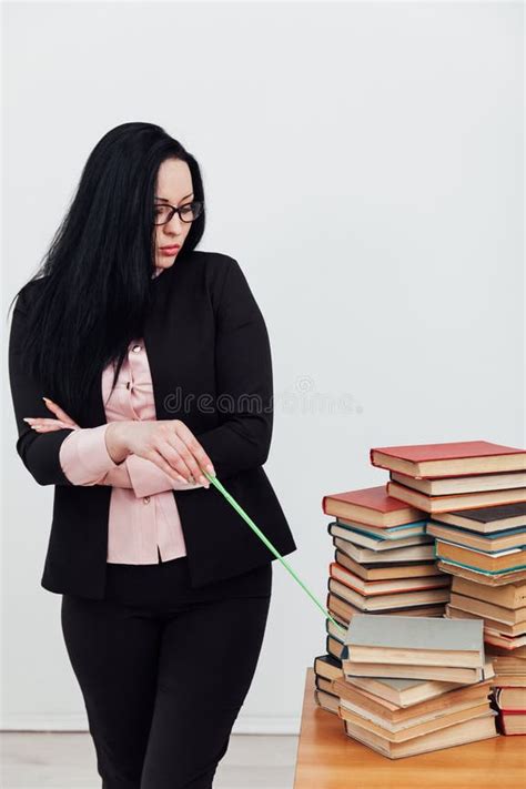 A Teacher With A School Pointer Points To A Stack Of Books To Read