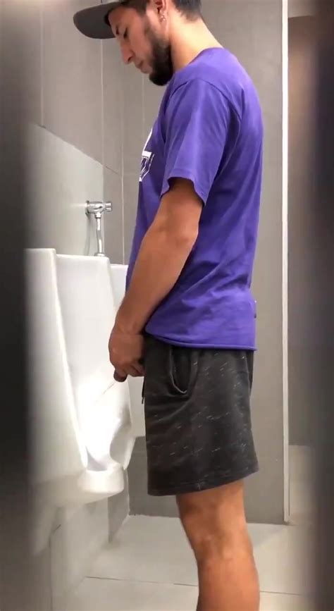 Cap And Shorts Pissing At The Urinal