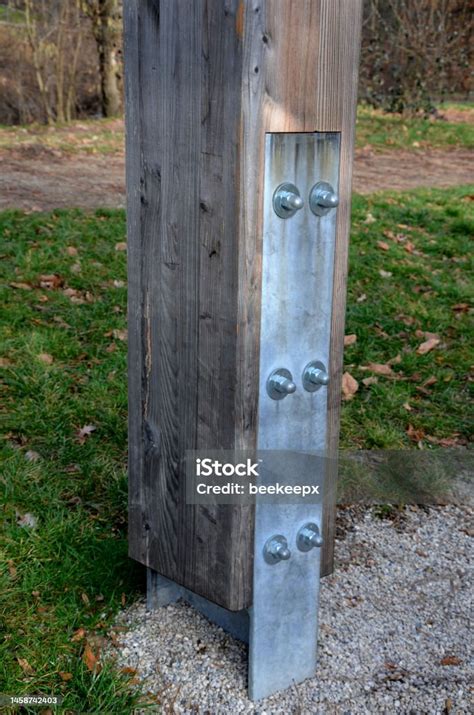 사각형 게이트 또는 프레임 모양의 거대한 목재 빔 그 사이에는 어린이를위한 그네가있는 금속 막대가 있습니다 공원 길 옆 잔디밭 지붕 금속판 공중 보도 전망 잔디밭 0명에