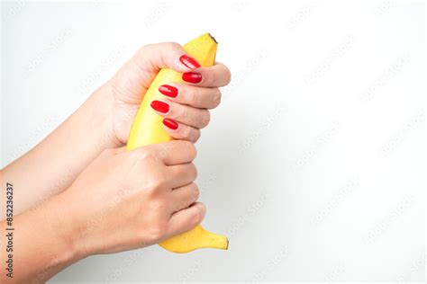 Hands Of A Woman With Bright Red Nail Polish Holding Large Curvy Banana