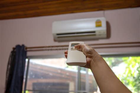 Woman Hand Holding Remote Control Directed To Air Conditioner Adjust Cold Temperature Close Up
