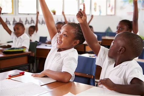 Students In Classroom Raising Hands