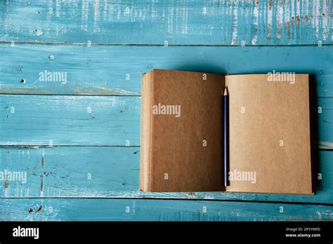 Top View Of Blank Open Notebook On Blue Wooden Background With Purple Pencil In Middle Working