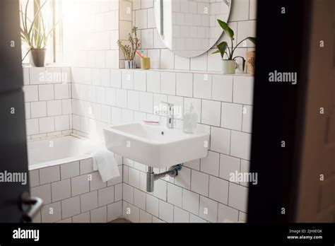 A Clean And Tidy Bathroom Inside A House A Basin Bath With Ceramic Tiling And A Round Mirror