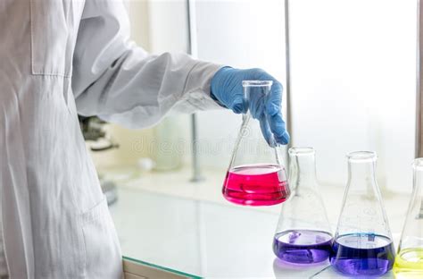 Scientist In A Laboratory Holding A Volumetric Flask Containing A Purple Chemical Titration