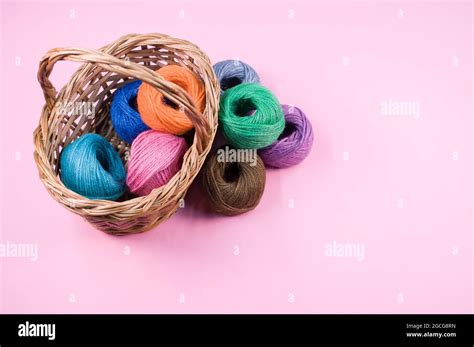 A Pile Of Colorful Textile Balls Of Wool In A Wicker Basket On Pink