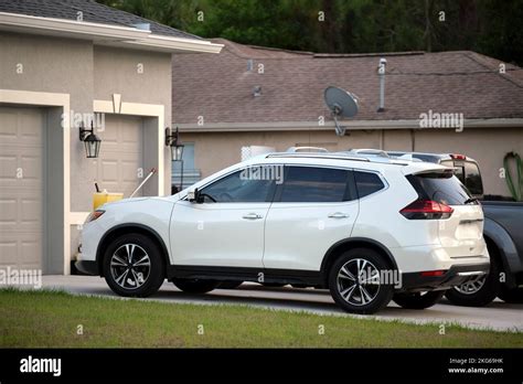 Car Parked In Front Of Wide Garage Double Door On Concrete Driveway Of