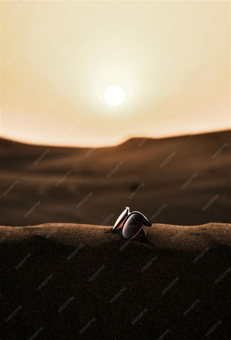 Premium Photo A Pair Of Sunglasses In The Desert With The Sun In The