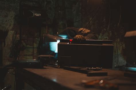 용접기 마스크의 작업자는 철 용접 작업장에서 일합니다 남자는 철 제품을 만든다 남자는 위험한 광선으로부터 자신의 눈을 보호하기 위해 마스크를 사용하여 용접 기계와 함께 작동