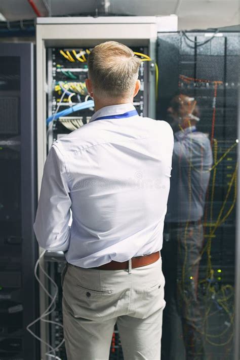 Connecting To The Main Server Rearview Shot Of A Mature Man Working In Connecting To The Main Server Rearview Shot Of A Mature Man Working In