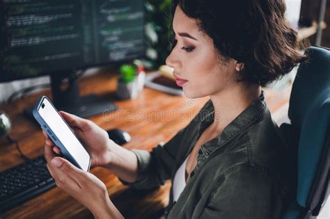 Female Programmer Using Smartphone While Working At Her Desk Coding On A Computer In A Stylish