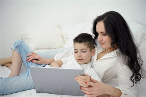 Madre E Hijo Sentados En La Cama Y Viendo La Tableta De Dibujos