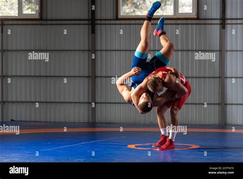 Two Greco Roman Wrestlers In Red And Blue Uniform Wrestling On A Blue