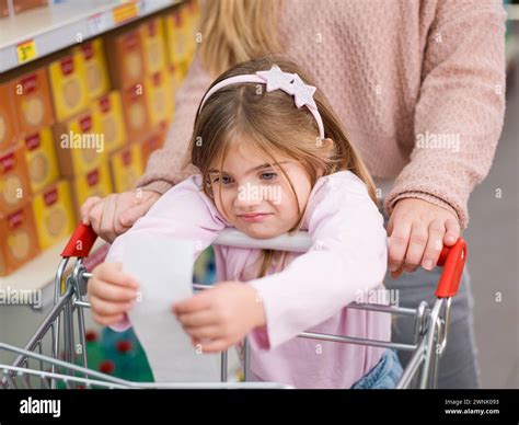 Disappointed Girl At The Supermarket With Her Mother She Is Holding A