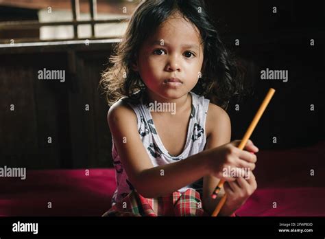 Portrait Of A Young Filipino Schoolgirl With A Serious Facial Expression She Sits On The Bed In