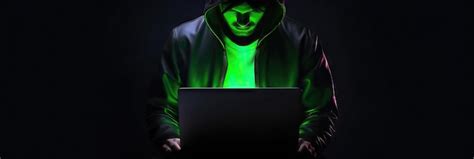 Premium Ai Image Hacker Without Face In A Hood Holds A Laptop On A Dark Background Banner
