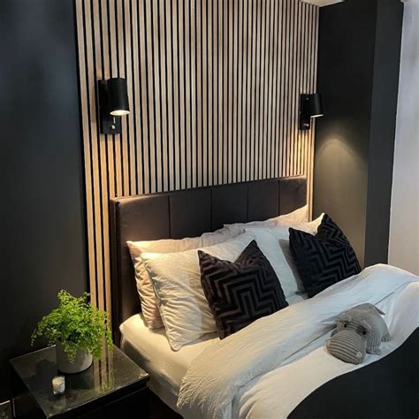 A Bed With White Sheets And Black Pillows In A Room Next To A Wall