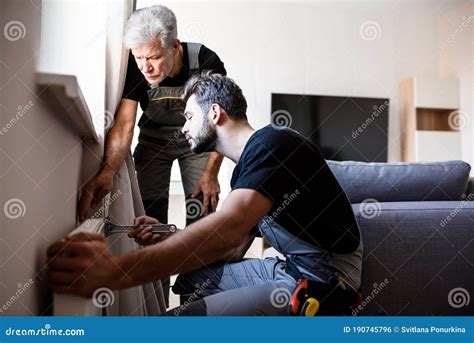 Two Professional Plumbers Workers In Uniform Fixing Or Installing Heating Radiator