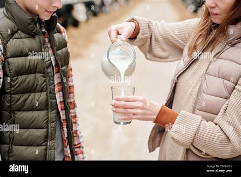Close Up Of Woman In Vest Pouring Fresh Milk From Pitcher To Son After