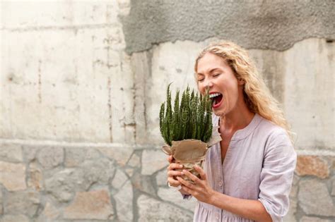 Angry Woman Holds Plant In Front Of Her Face And Screaming At It Stock