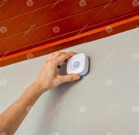 A Technician Installs A Modern Movement Detector In A Cozy Apartment