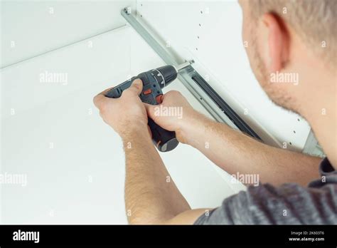 Male Hands Hold Cordless Electric Screwdriver Screw To Fix Rail