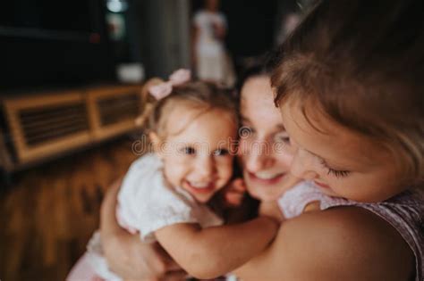 Mother Embracing Her Two Young Daughters With Love And Warmth In A Cozy