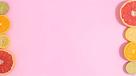 Pastel Pink Background With Sliced Citrus Fruits In Corners Copy Space