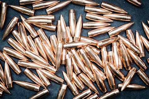 Brass Rifle Bullets Are Scattered Over A Blue Velvet Table Surface