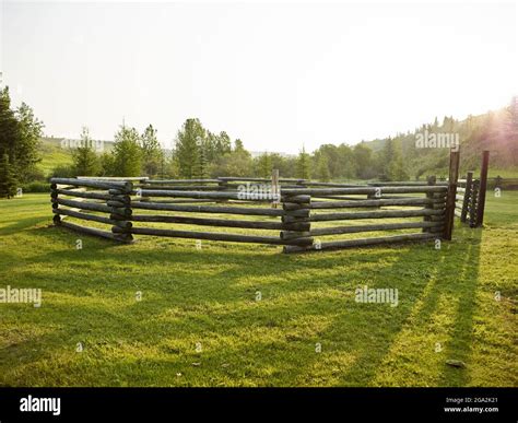 Empty Paddock With A Split Rail Fence On A Grassy Field Surrounded By